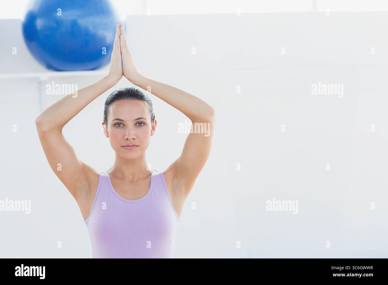 Woman wearing purple tank top raising arms above head in exercise ...