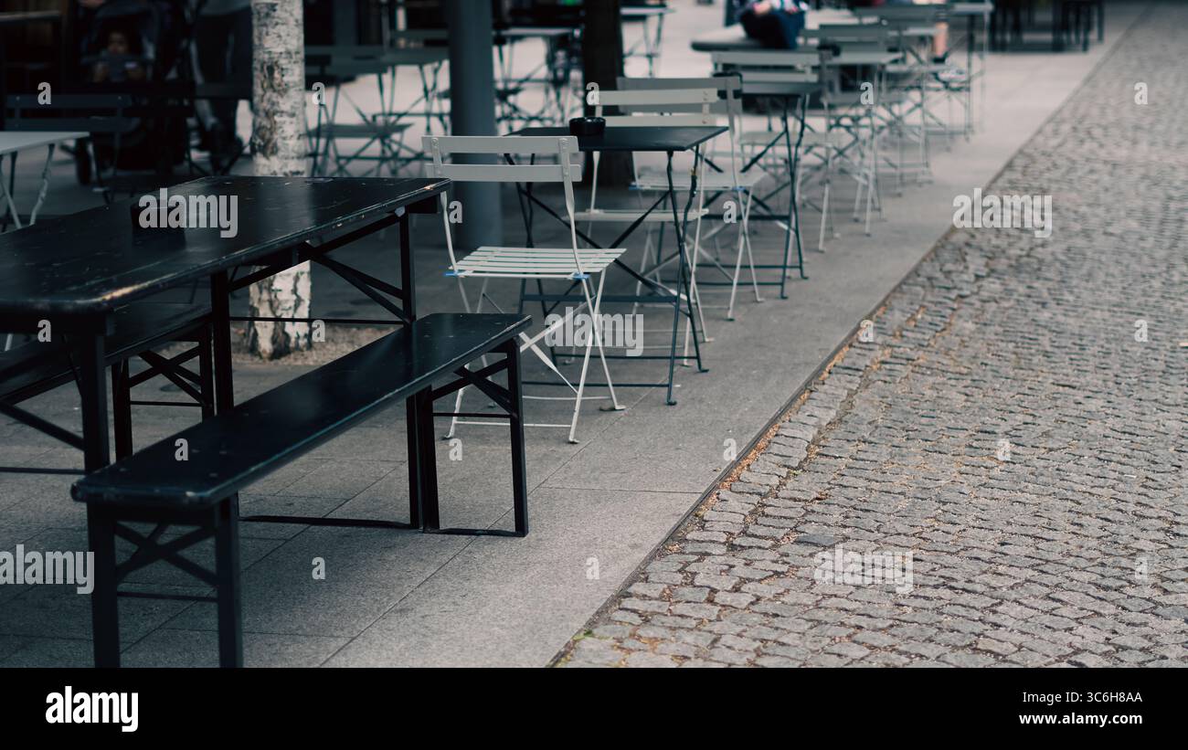 Simple outdoor tables and chairs in cozy sidewalk cafe with empty sunny ...