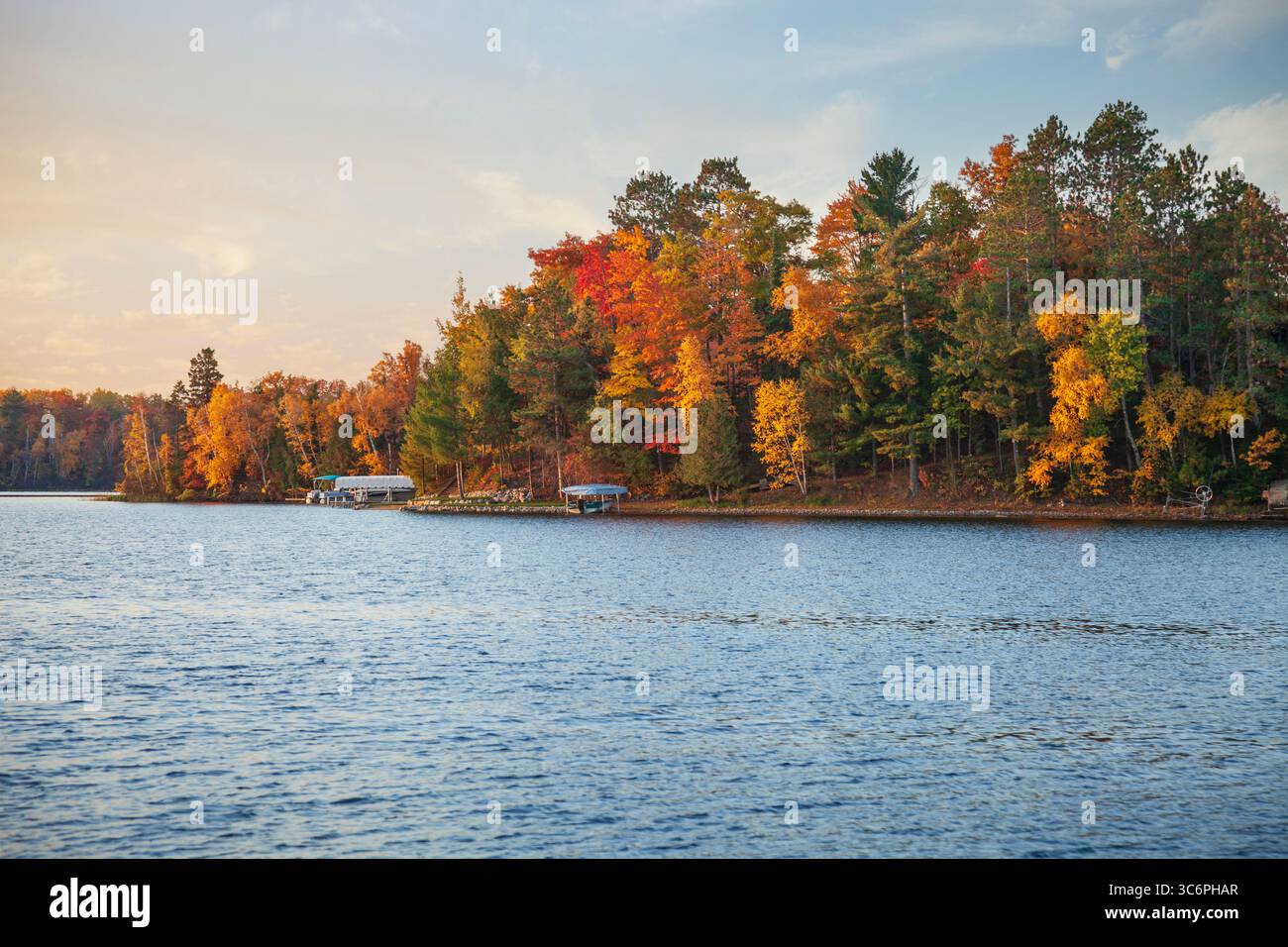 Shoreline with boats and trees in brilliant color during autumn in ...