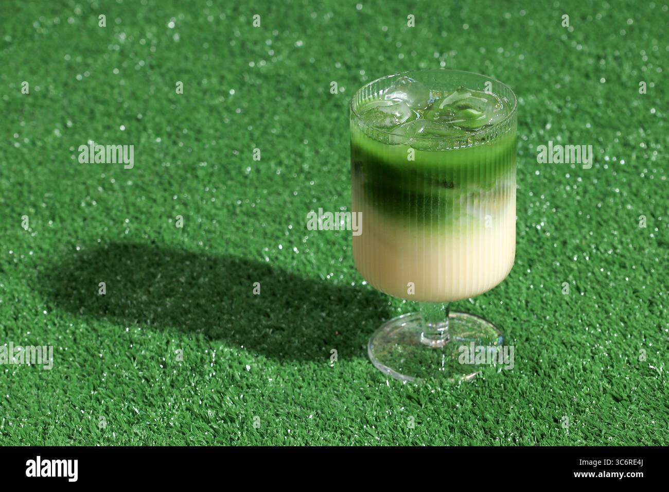 Iced Matcha Latte on a Green Grass Background, Served in Stem Glass ...