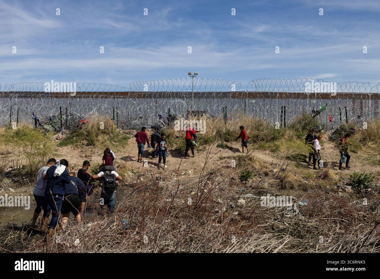 Civilians, including children, cross rugged terrain near the heavily ...