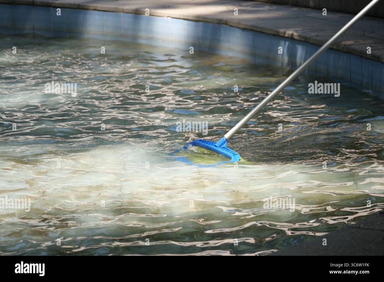 Cleaning a pool with a skimmer in sunny weather Stock Photo - Alamy