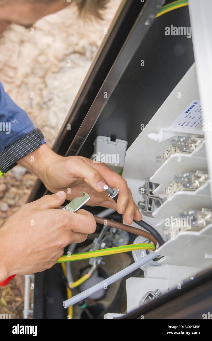 Person installing electrical cables in a switch box with tools ...
