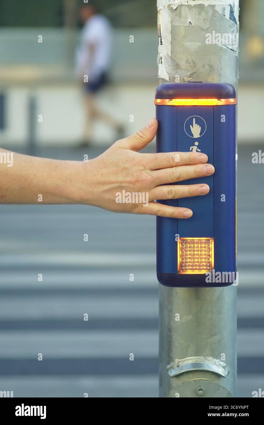 Pedestrian activates crosswalk button by hand to send signal request to ...