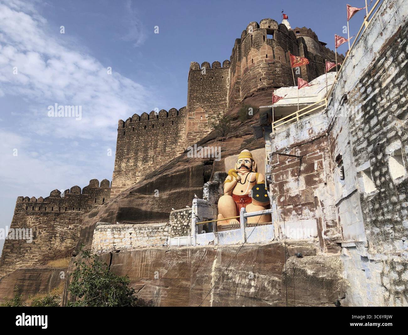 Large fort with a statue and flags under a clear sky, Mehrangarh Fort ...