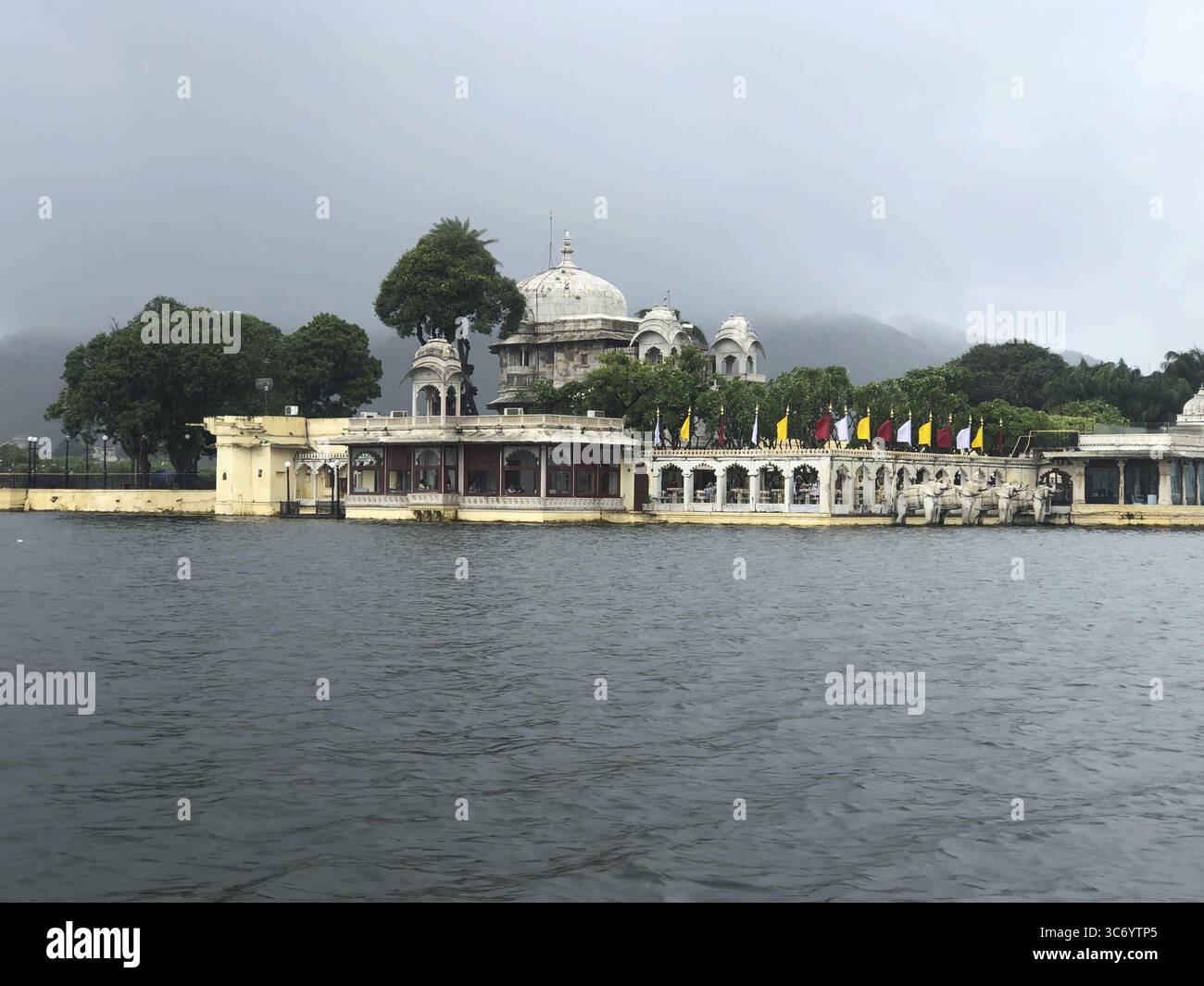 An imposing lakeside palace surrounded by lush greenery and magnificent ...