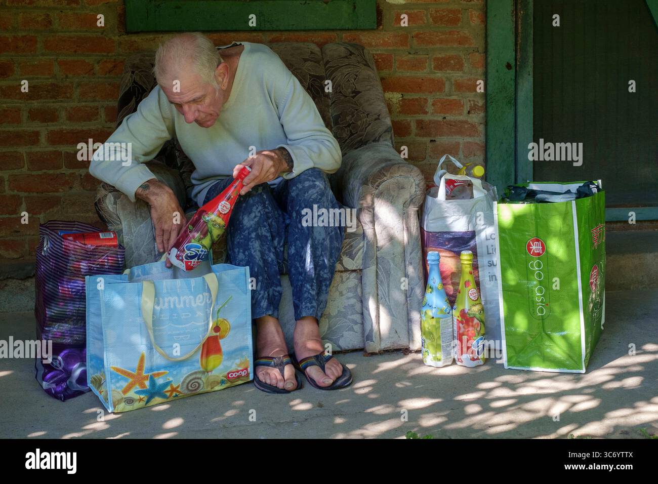 older man sorting bottles and cans into bags ready for recycling Stock ...