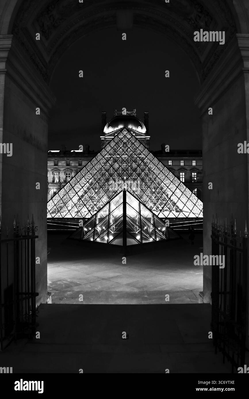 Night view of the Louvre Pyramid framed by an archway, highlighting its ...
