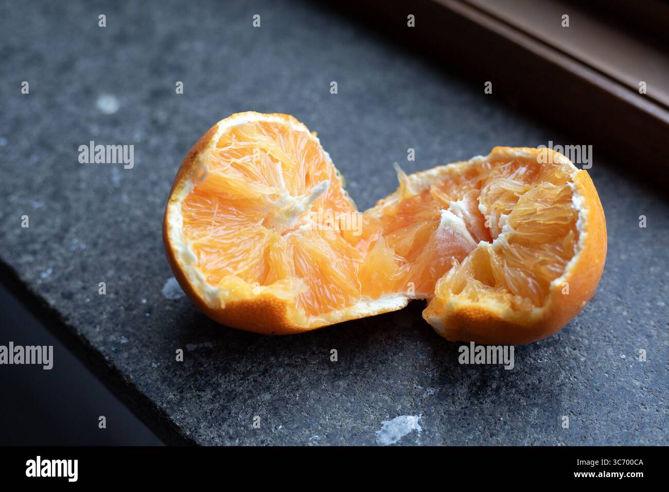 An orange that has been partially peeled is resting on a counter Stock ...