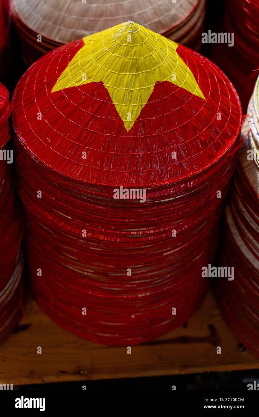A market stall displays stacks of traditional Vietnamese conical hats ...