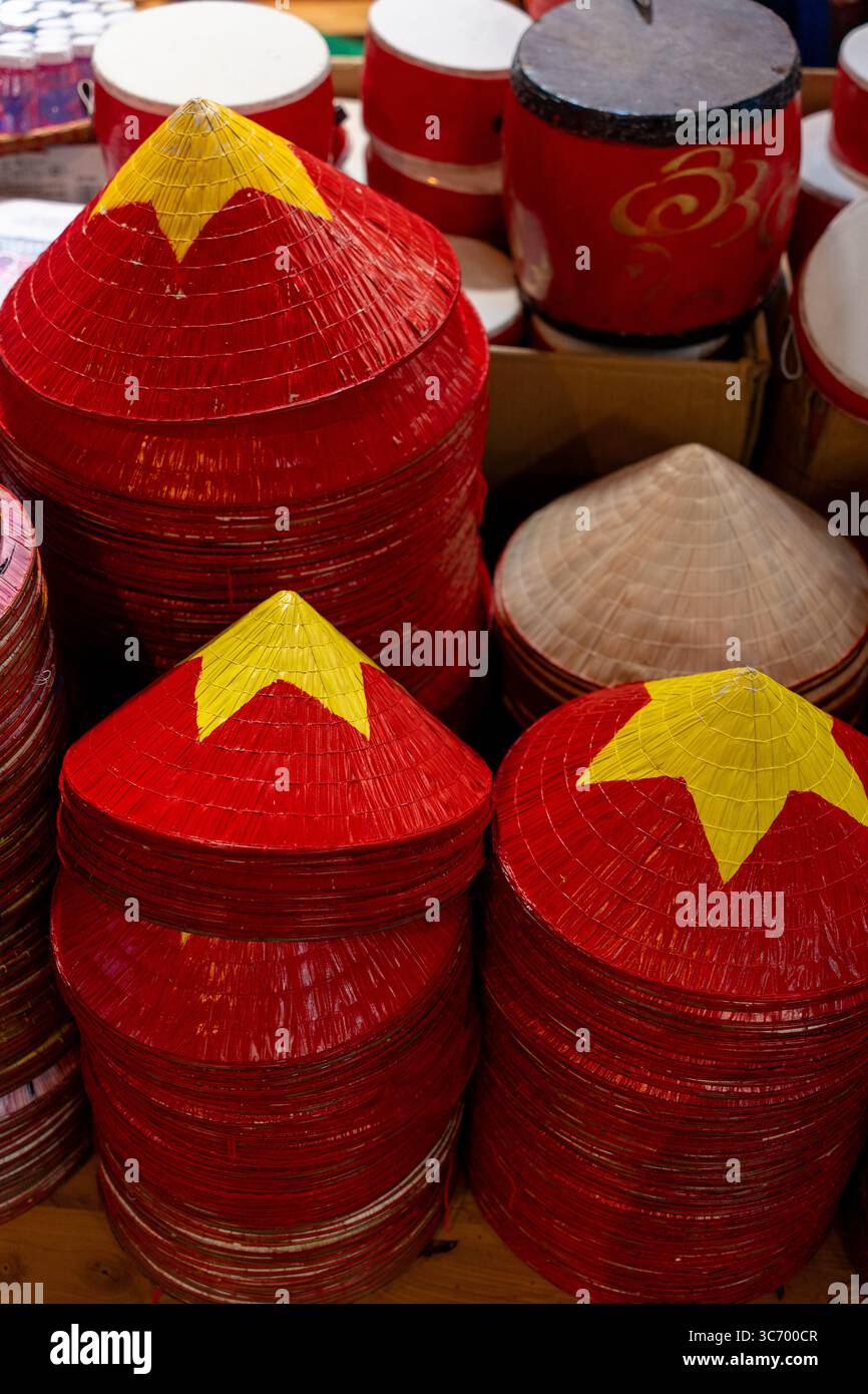 A market stall displays stacks of traditional Vietnamese conical hats ...