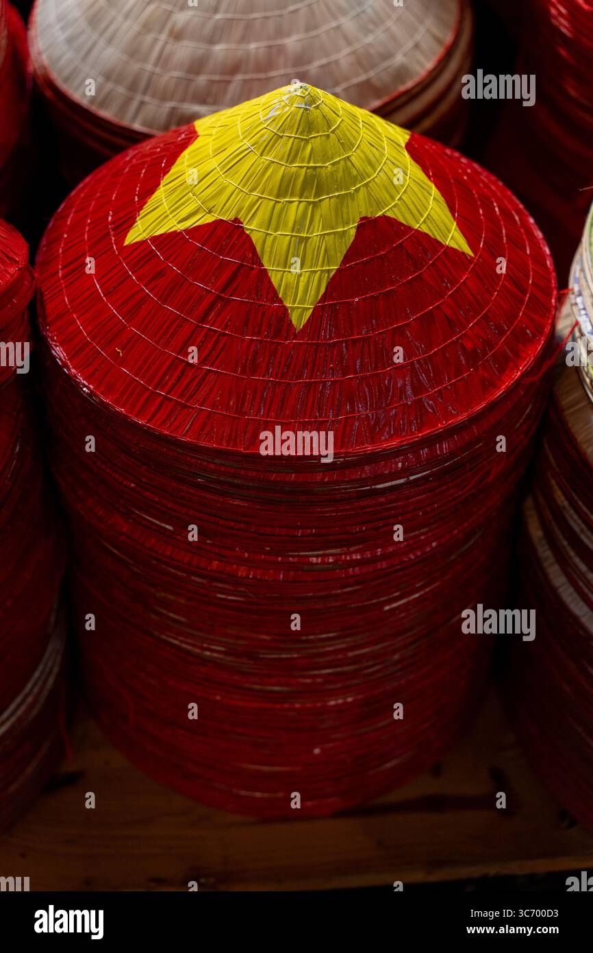 A market stall displays stacks of traditional Vietnamese conical hats ...