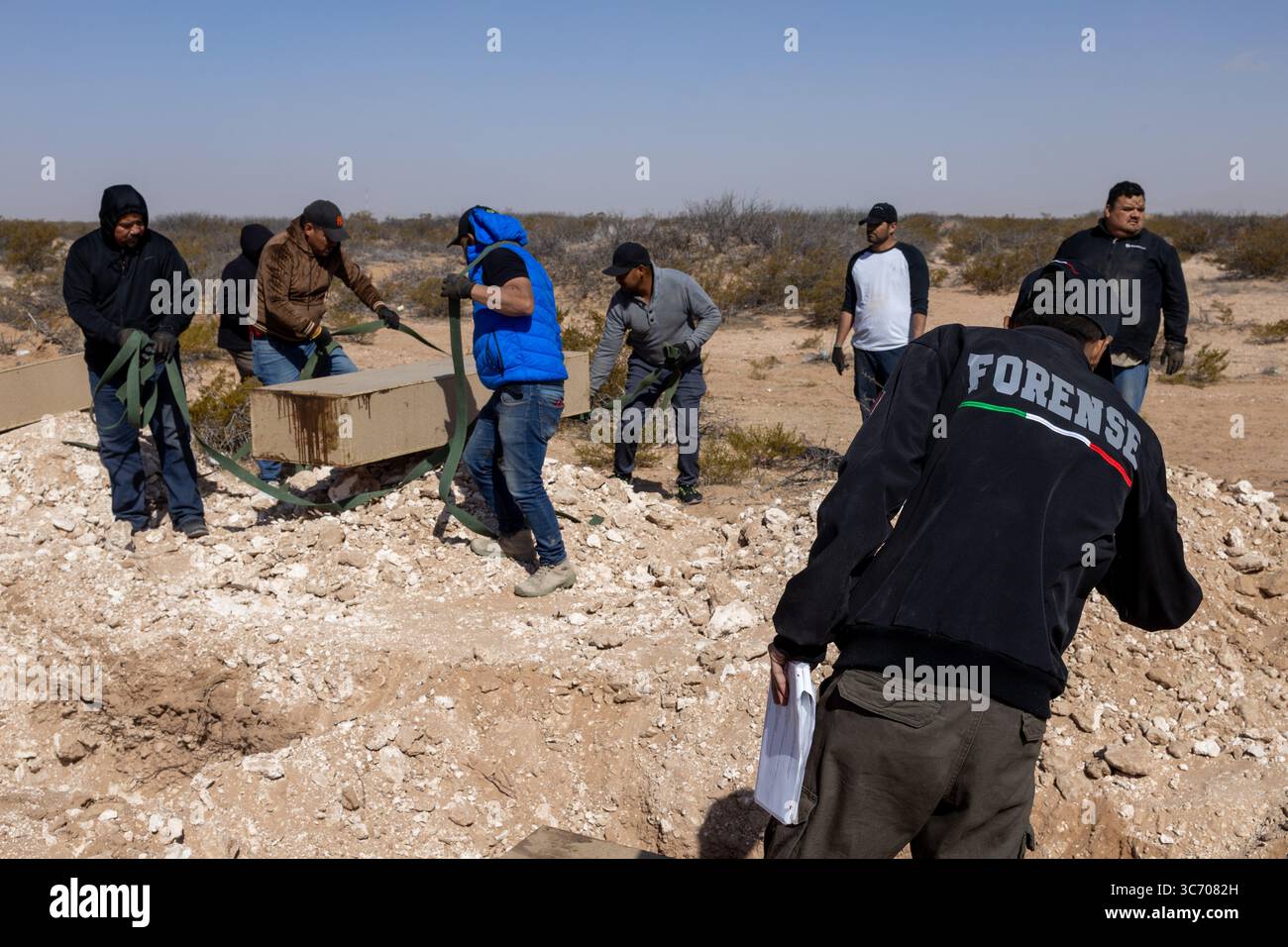 Forensic workers in Ciudad Juarez move a metal object in a crime scene ...