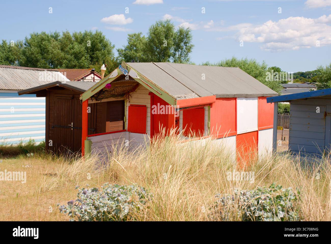 Painted beach huts behind sand dunes Stock Photo - Alamy