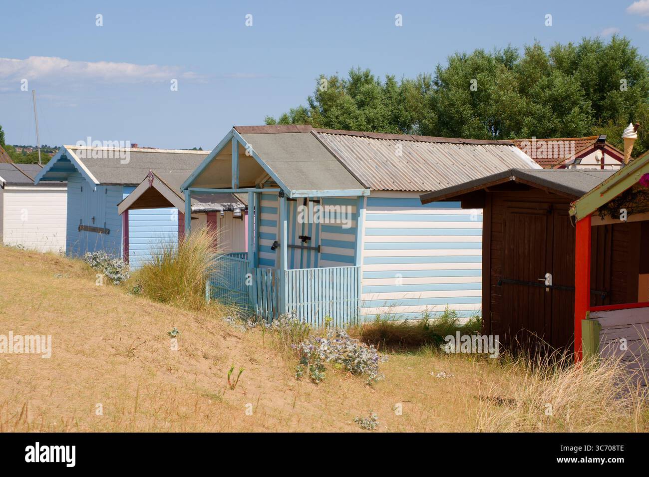 Painted beach huts behind sand dunes Stock Photo - Alamy
