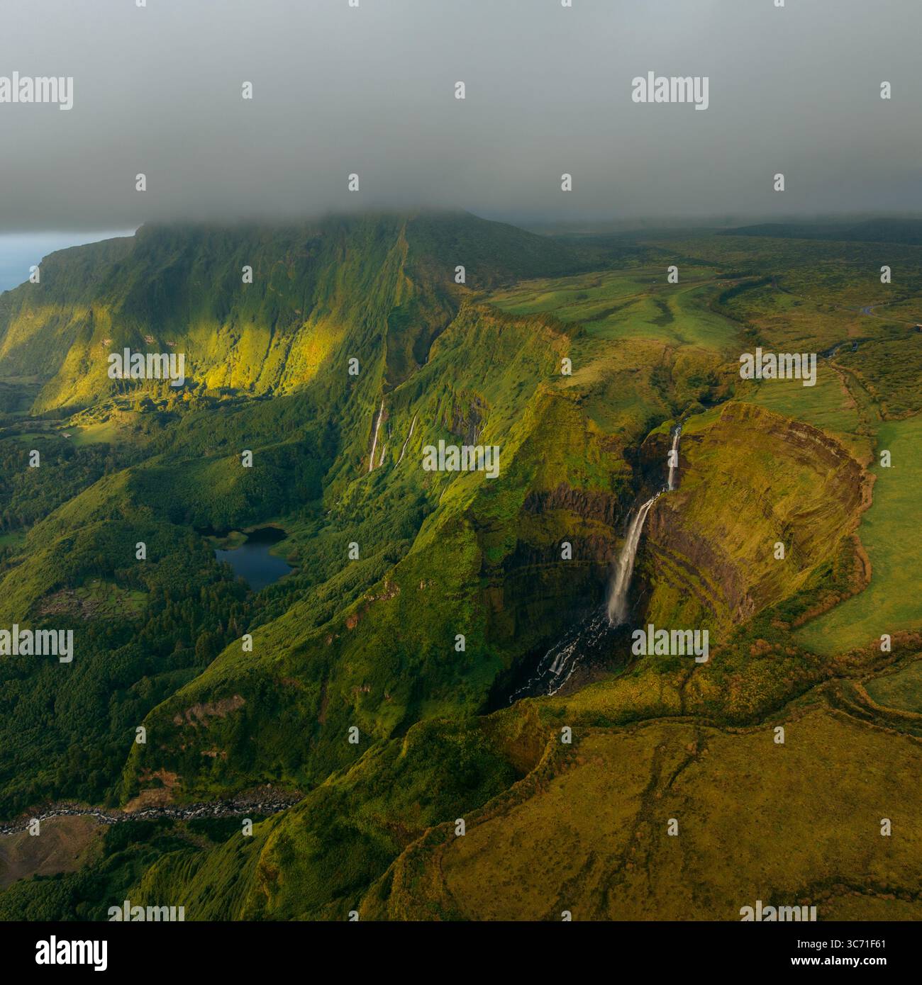 Aerial view of cascading waterfalls plunge down verdant cliffs into ...