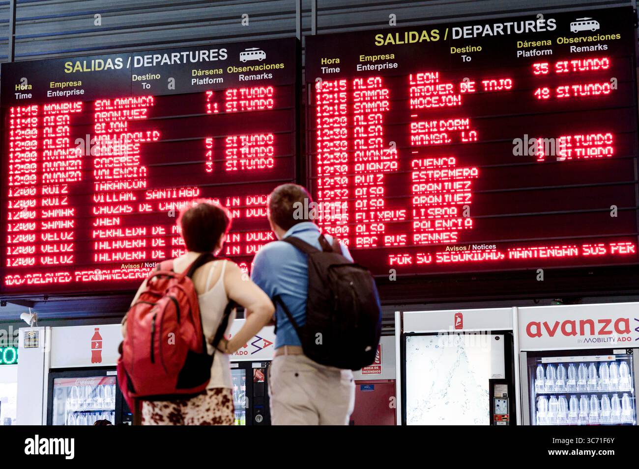 Several people with suitcases look at the departures panel at the ...