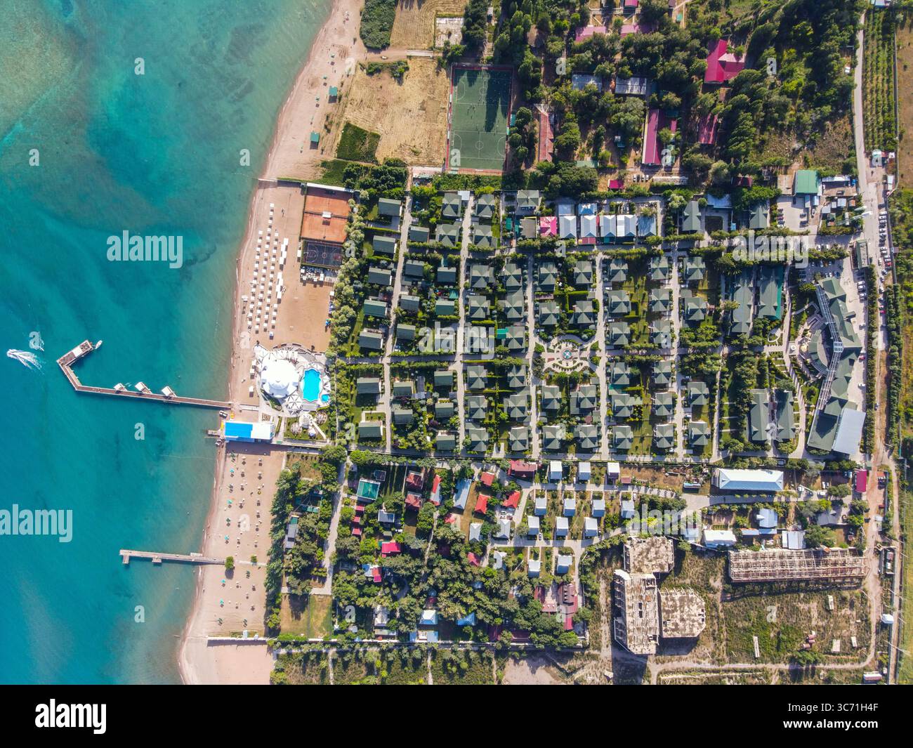 A wide top-down aerial view of a large beach resort with a swimming ...