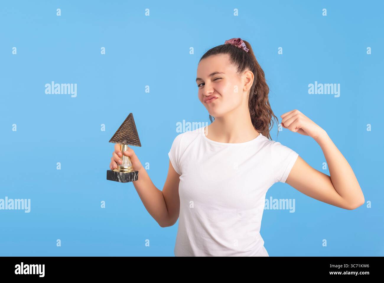 Proud teen girl flexing her arm and holding a trophy. Concept of ...