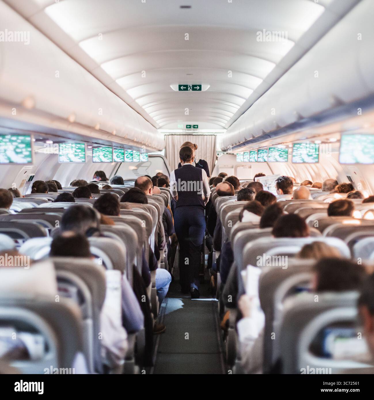 Interior of airplane with passengers on seats and stewardess in uniform ...