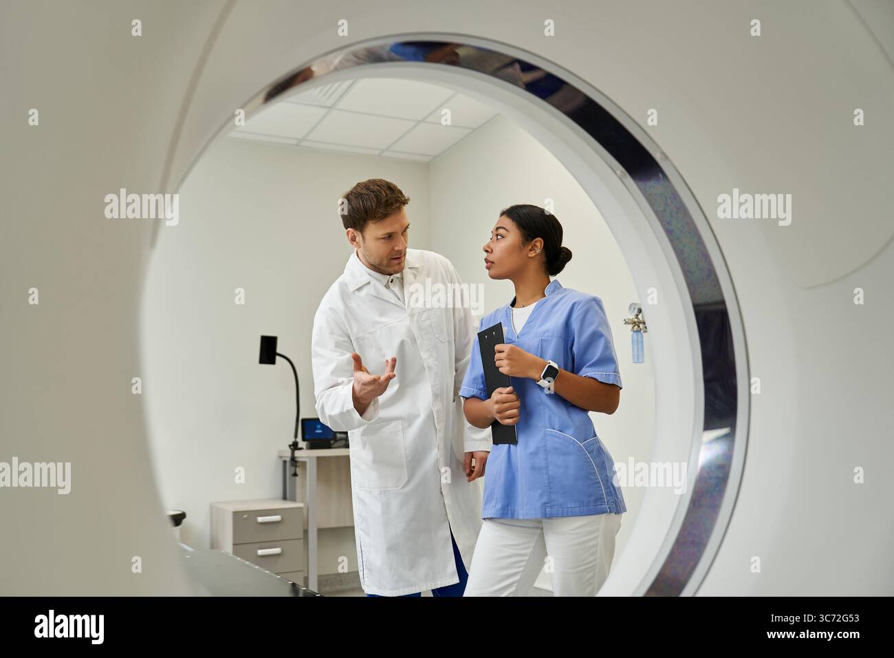 Two healthcare professionals discuss MRI scanner protocols in a state ...