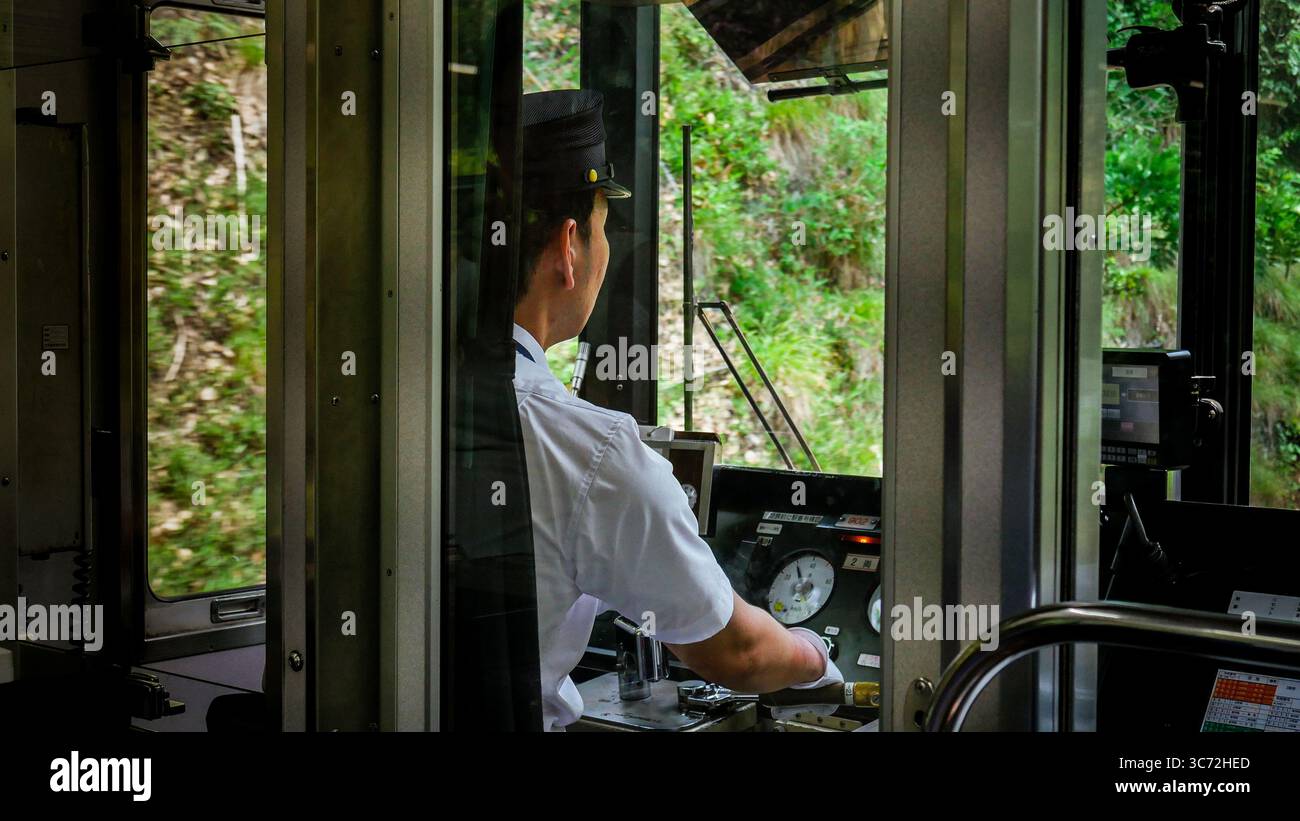 Japanese train driver operating cockpit controls through scenic ...