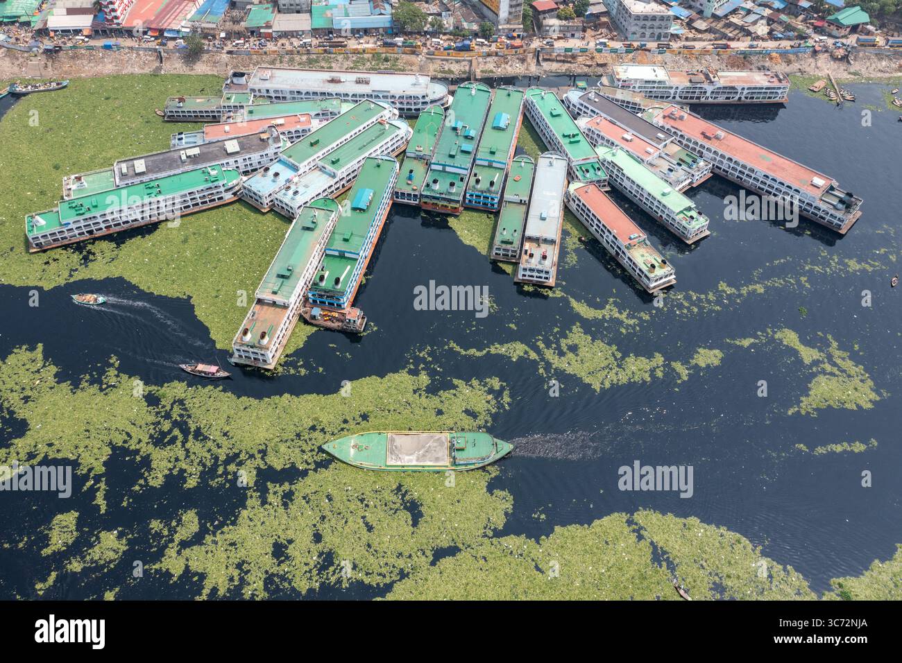 Aerial view of ferries docked along the Buriganga River, amidst a swirl ...