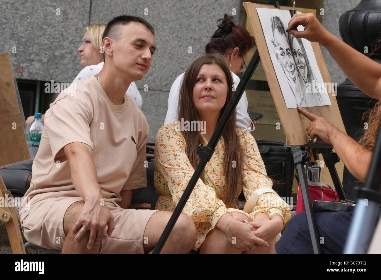 A couple pose for caricature portraits from a street artist in St ...