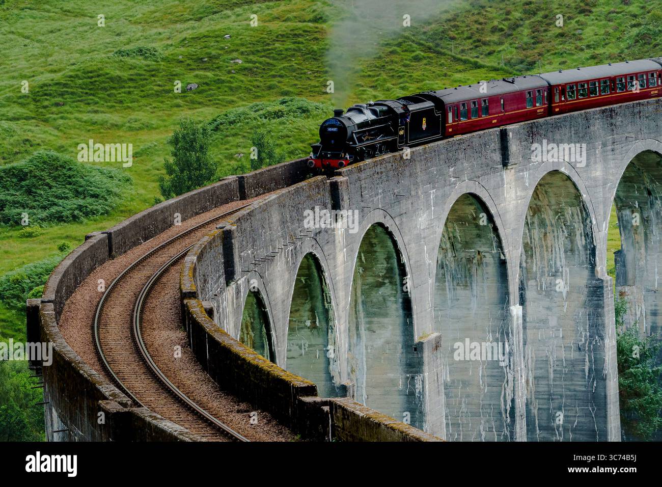 Jacobite steam train crossing the iconic Glenfinnan Viaduct in the Scottish Highlands, famous as ...