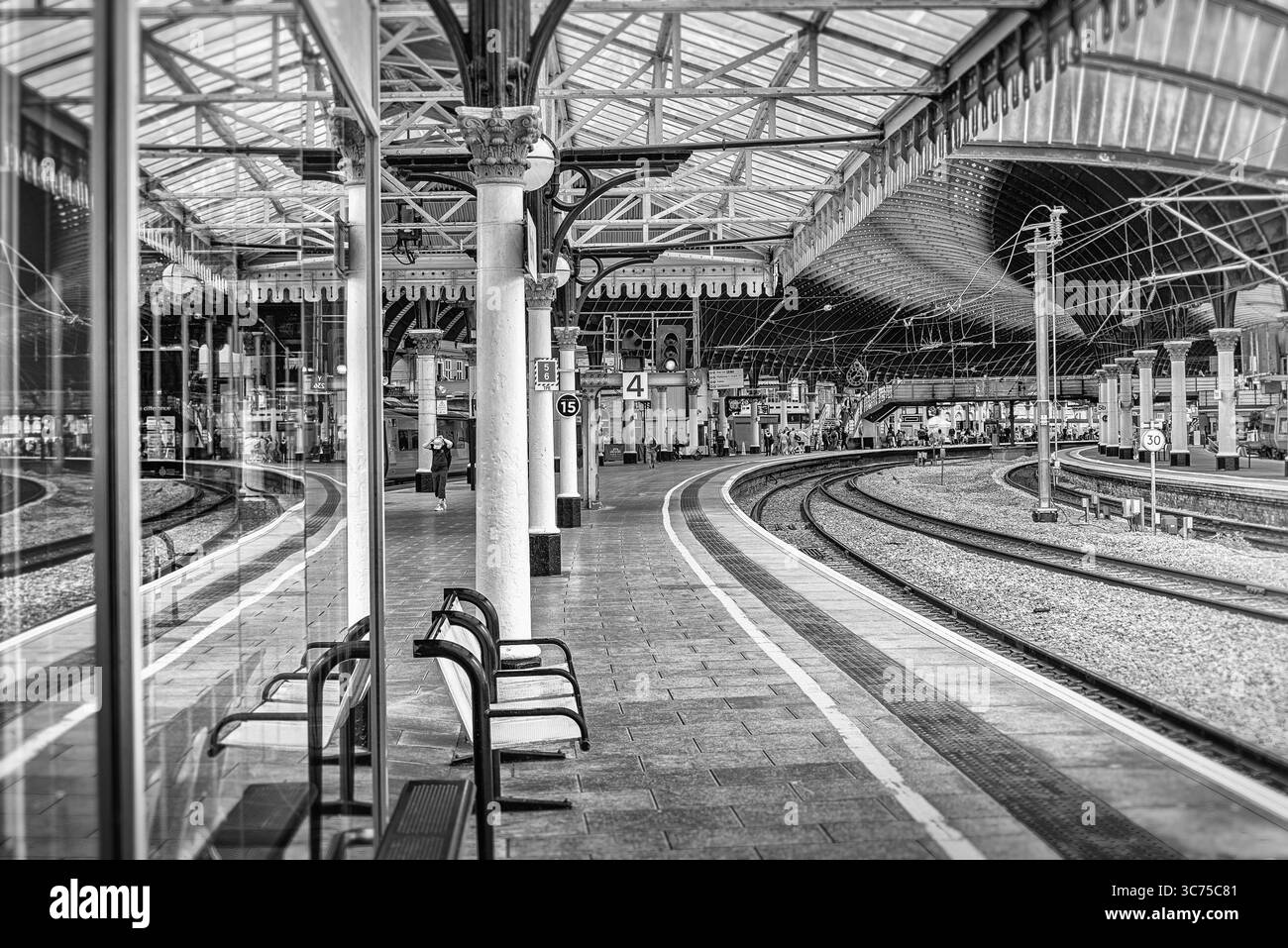 A railway station platform, lined by columns, curves, into a main ...