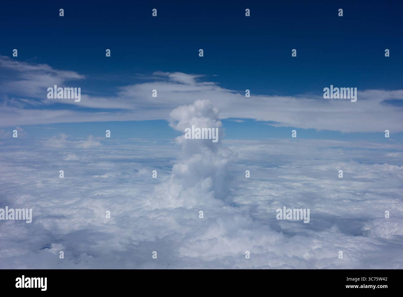 An ethereal view from above the clouds, with a towering, dense cumulus ...