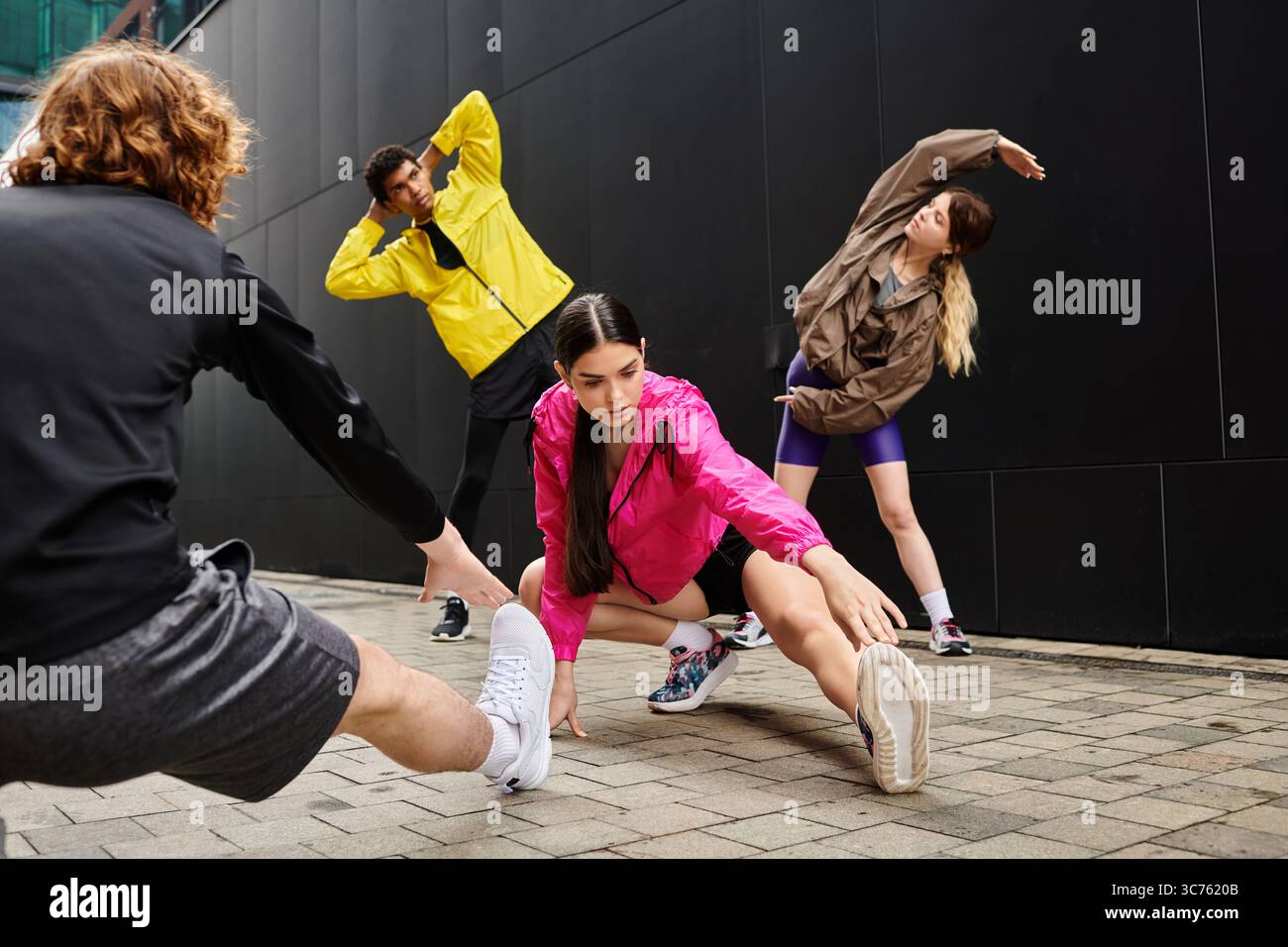 Group of young, sporty individuals engaging in dynamic stretching ...