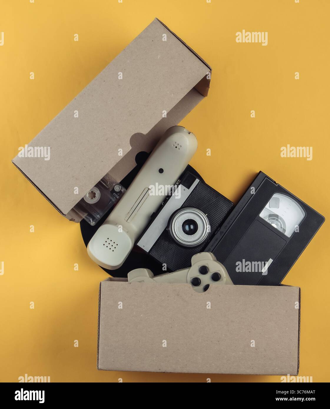 Cardboard box with video cassette, retro film camera, gamepad, vinyl ...