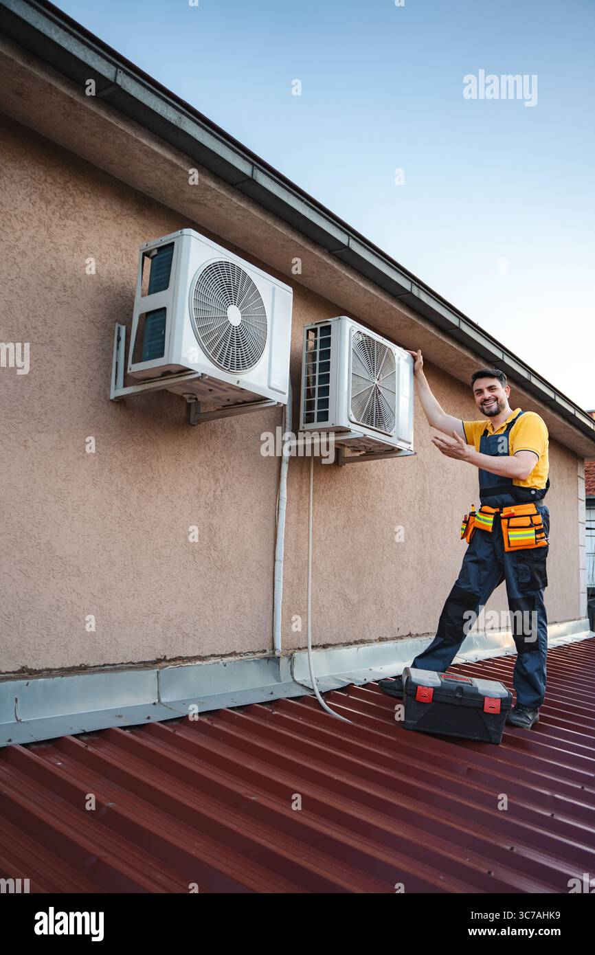 HVAC technician installing an air conditioner on a building rooftop ...