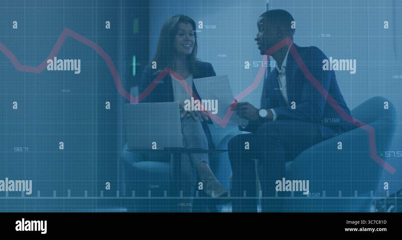 Two colleagues in business attire reviewing chart overlay using laptops ...