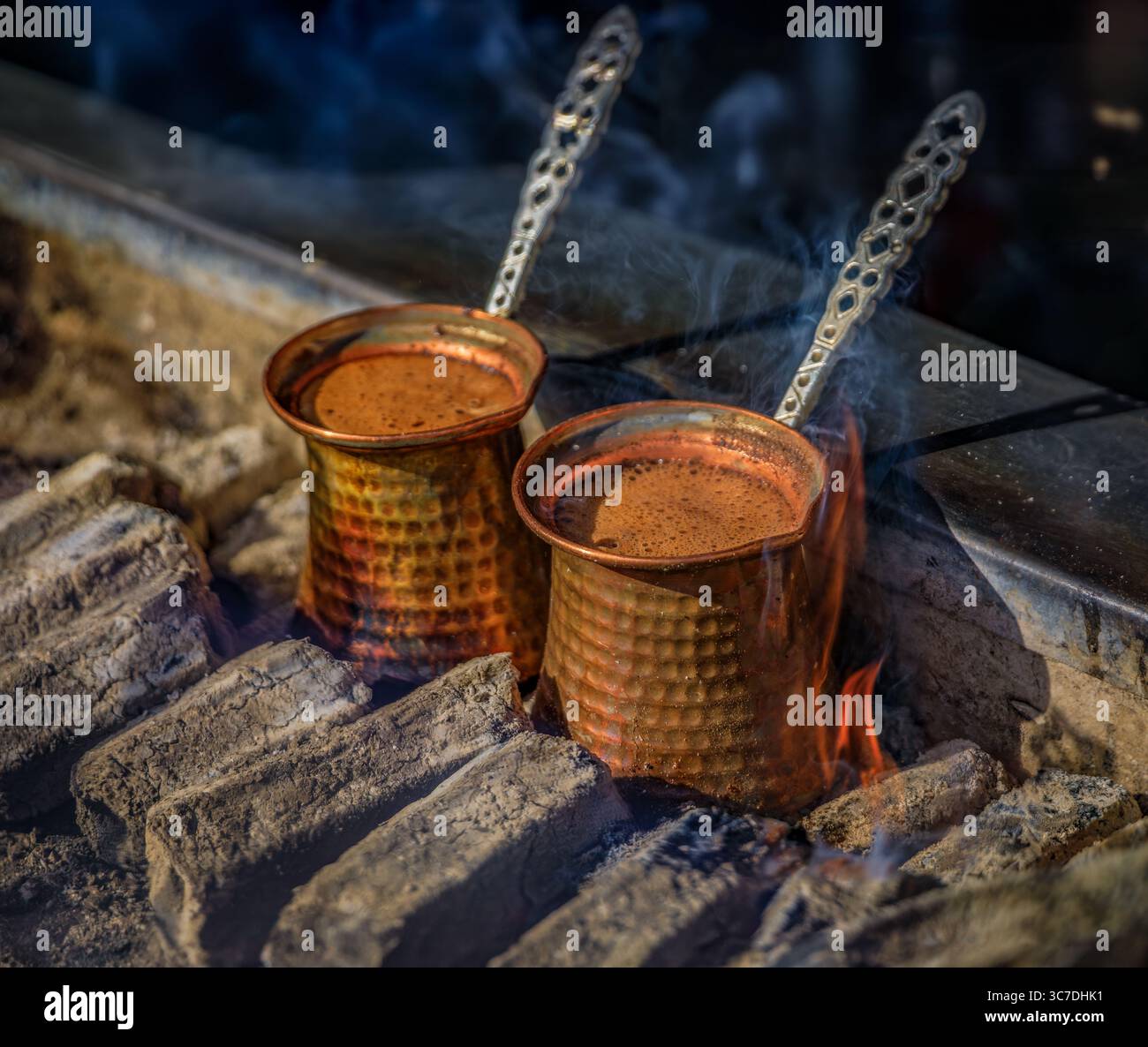 Cooking fresh aromatic traditional Turkish coffee on charcoal in cezve ...