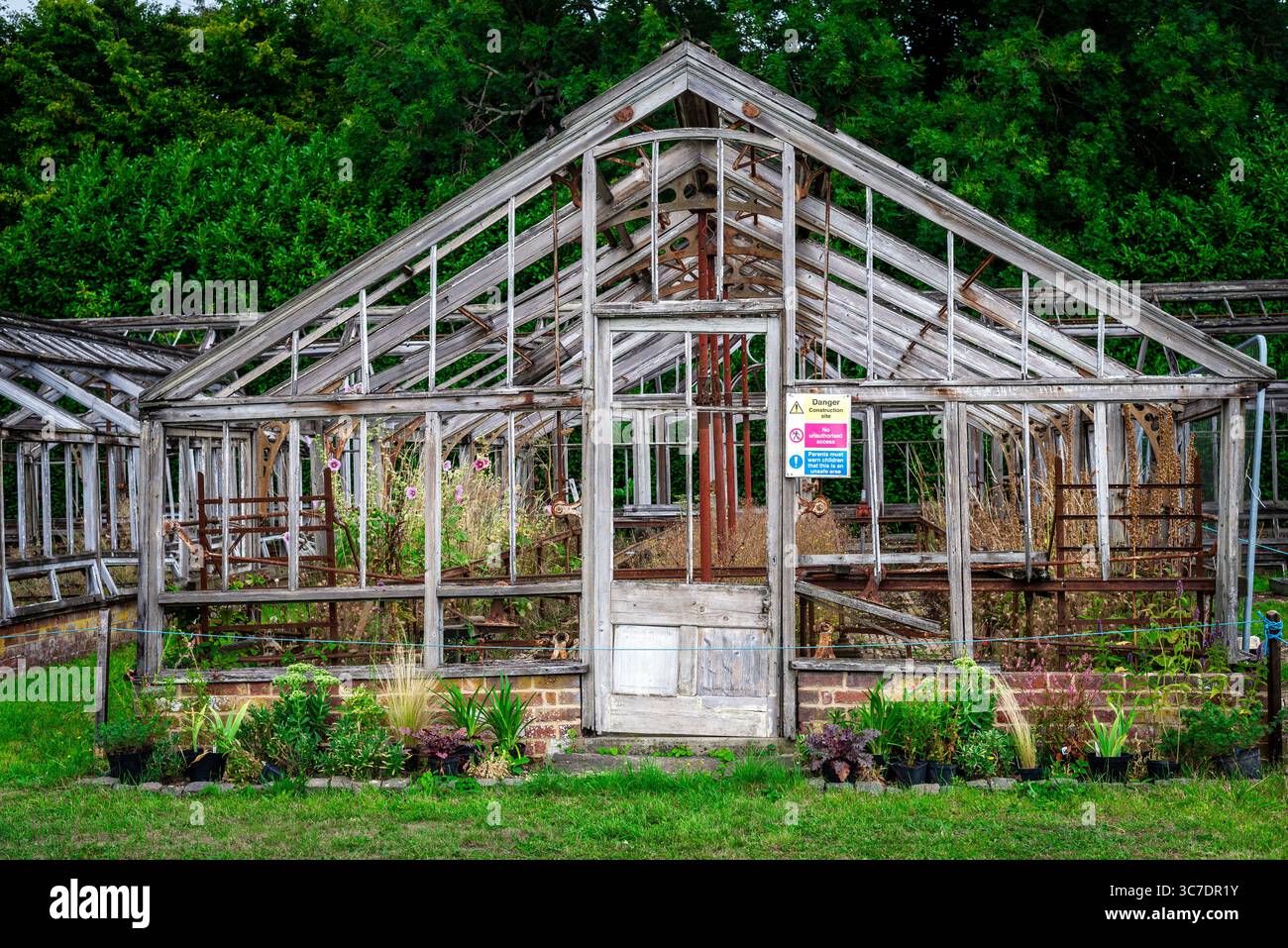 Dilapidated greenhouse showing danger warning sign at Luton Hoo Walled ...