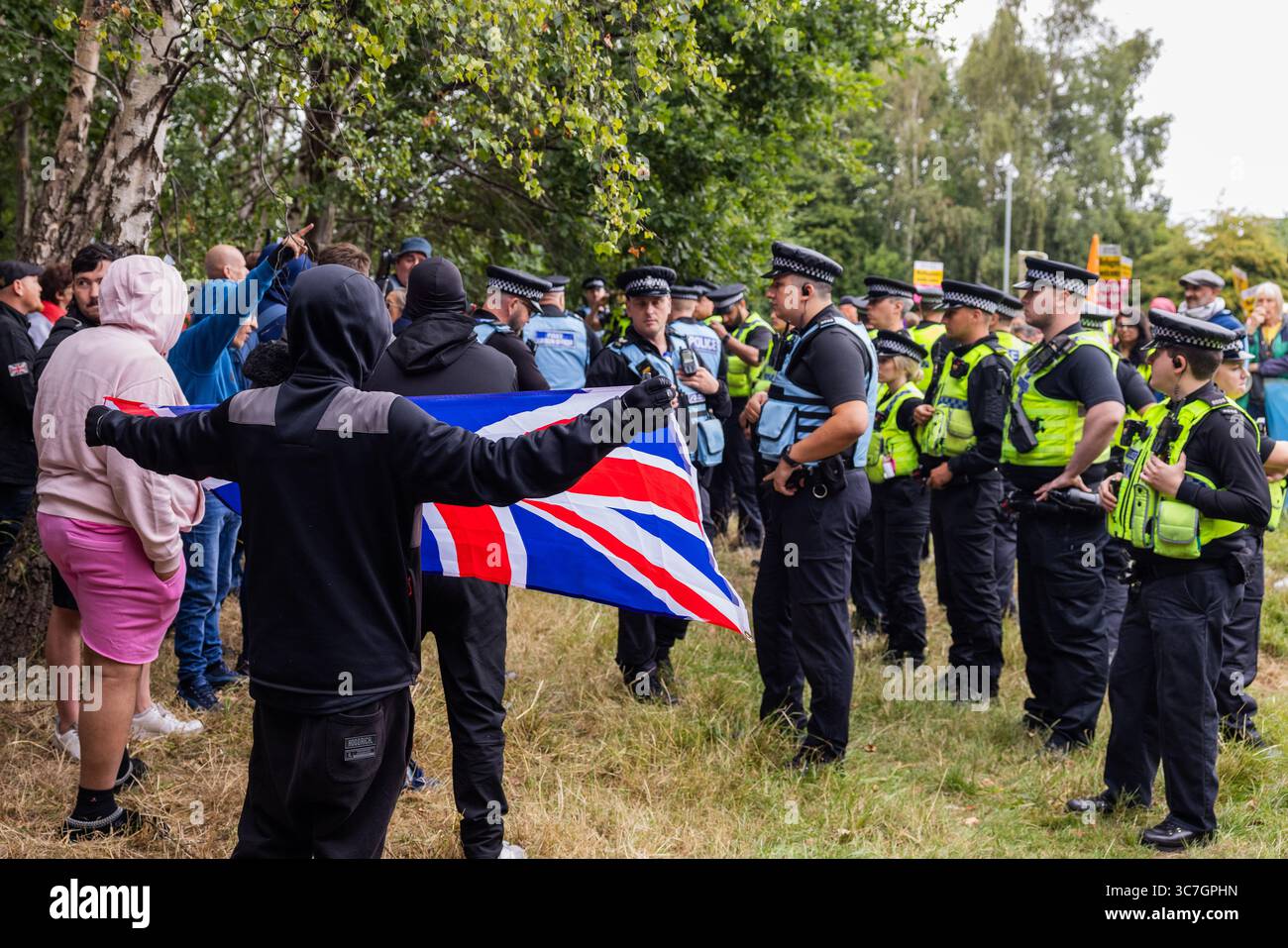 Leeds, UK. 01 AUG, 2025. Person holds a Union Jack Flag as opposing ...