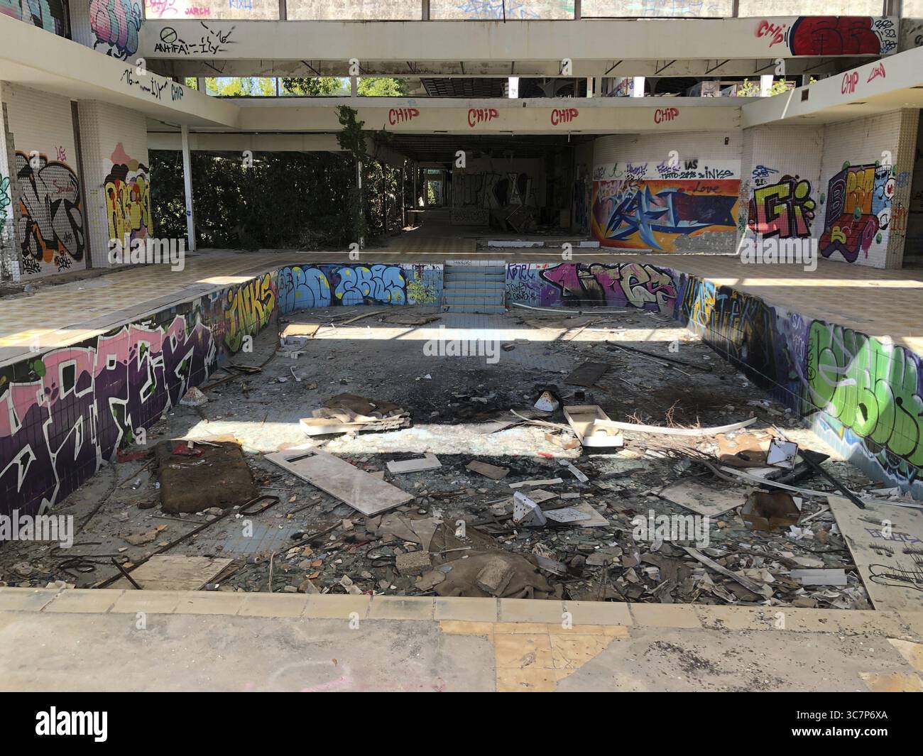Abandoned swimming pool with graffiti and concrete remains, surrounded ...