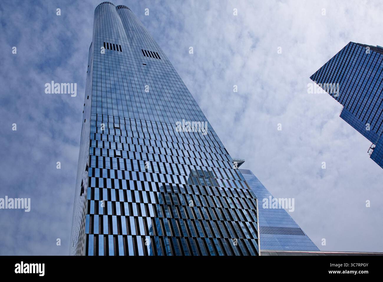 Reflective facade of 30 Hudson Yards skyscraper rises into a cloudy sky ...