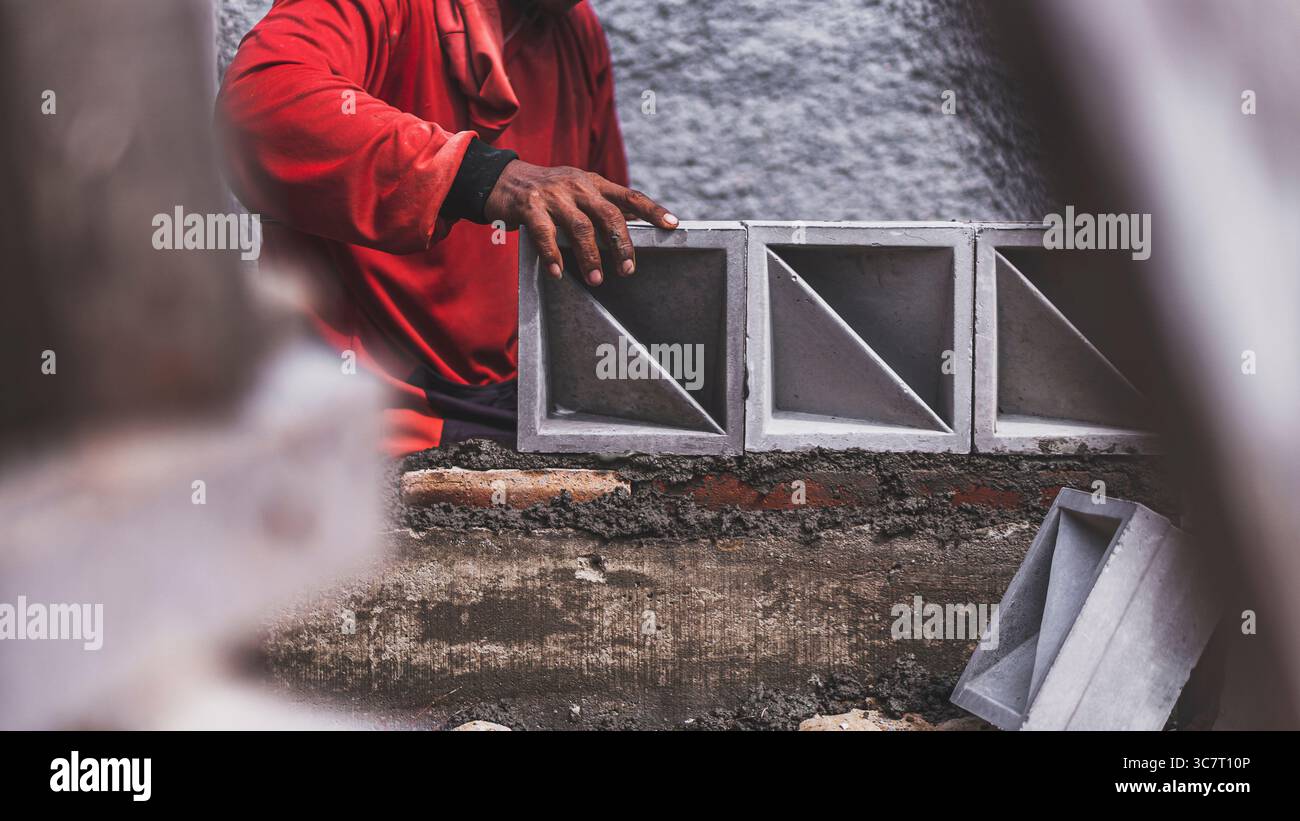 A construction worker carefully installs ventilation blocks, creating ...