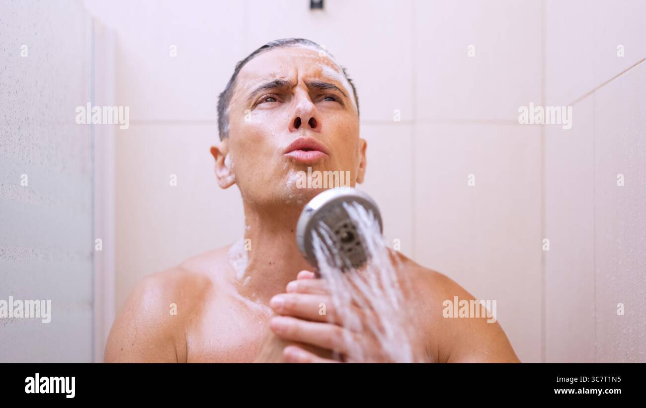 Man singing in shower using showerhead as microphone Stock Photo - Alamy