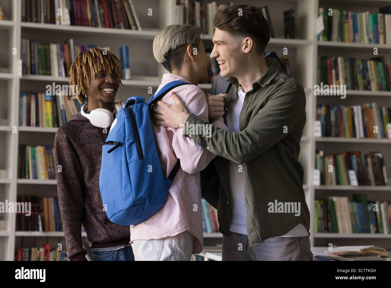Two diverse young student guys share hug handshake with laughter Stock ...