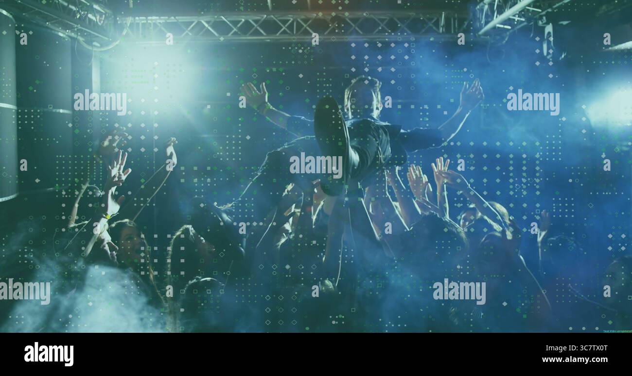 Riding male crowd-surfer being held aloft by fans in club space, with ...