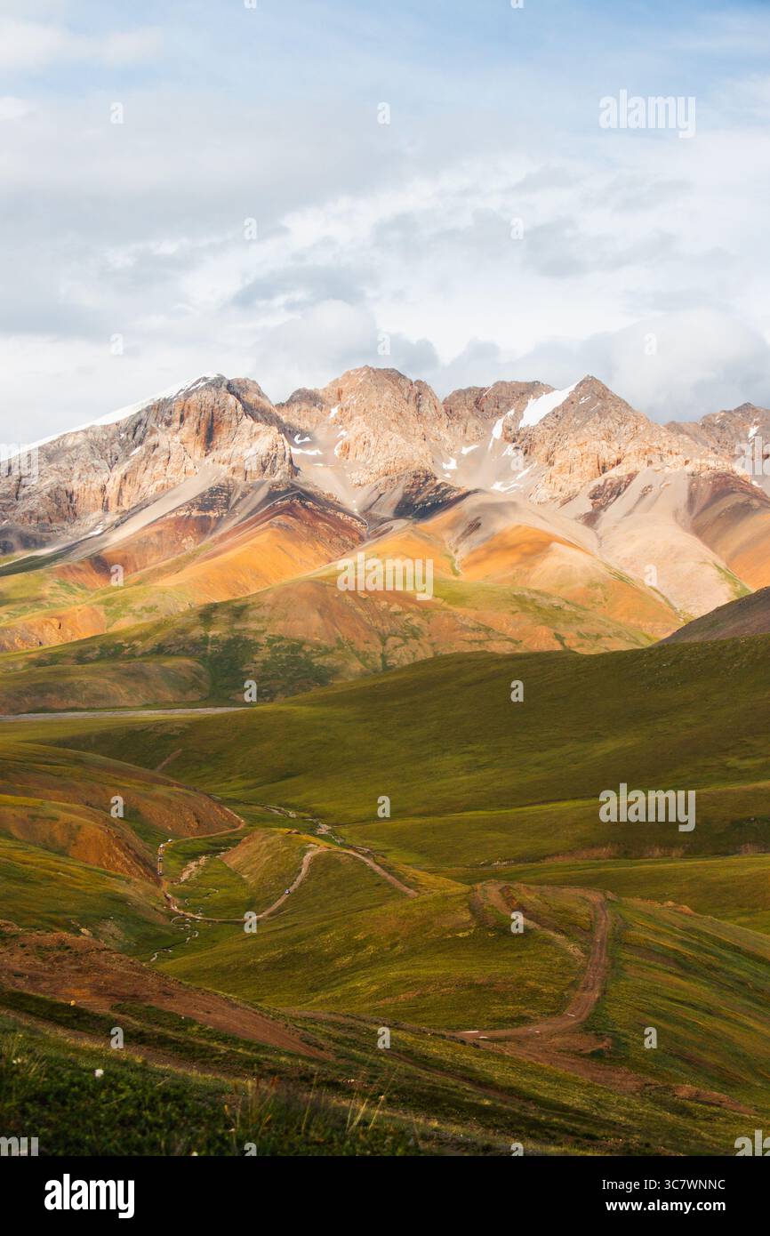 A serpentine dirt road winds through vibrant green hills, leading ...