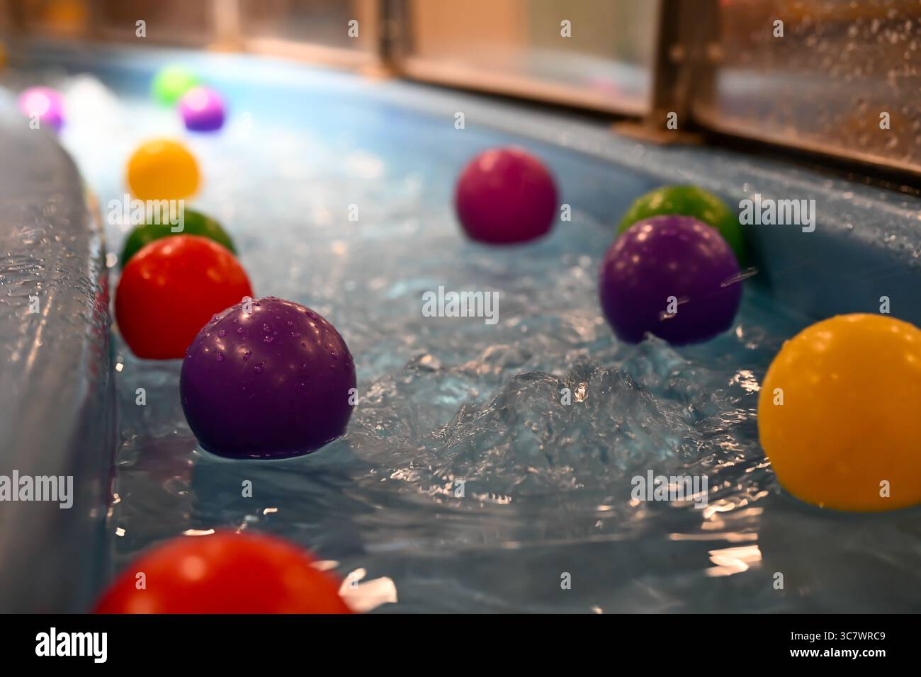 Colorful balls float along a water channel in an indoor play area ...