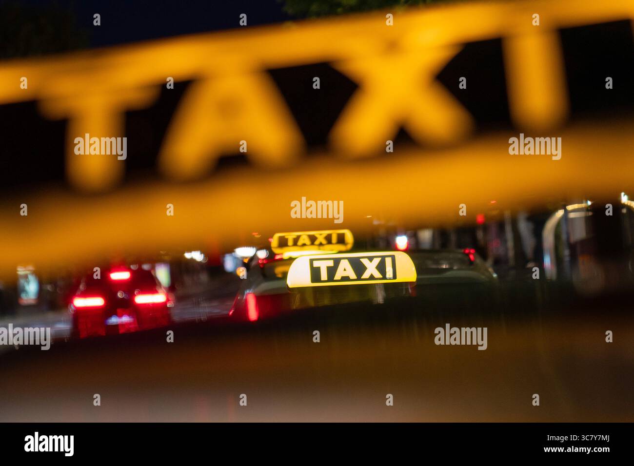 31 July 2025, Berlin: Cab signs light up the city in the evening. Photo ...