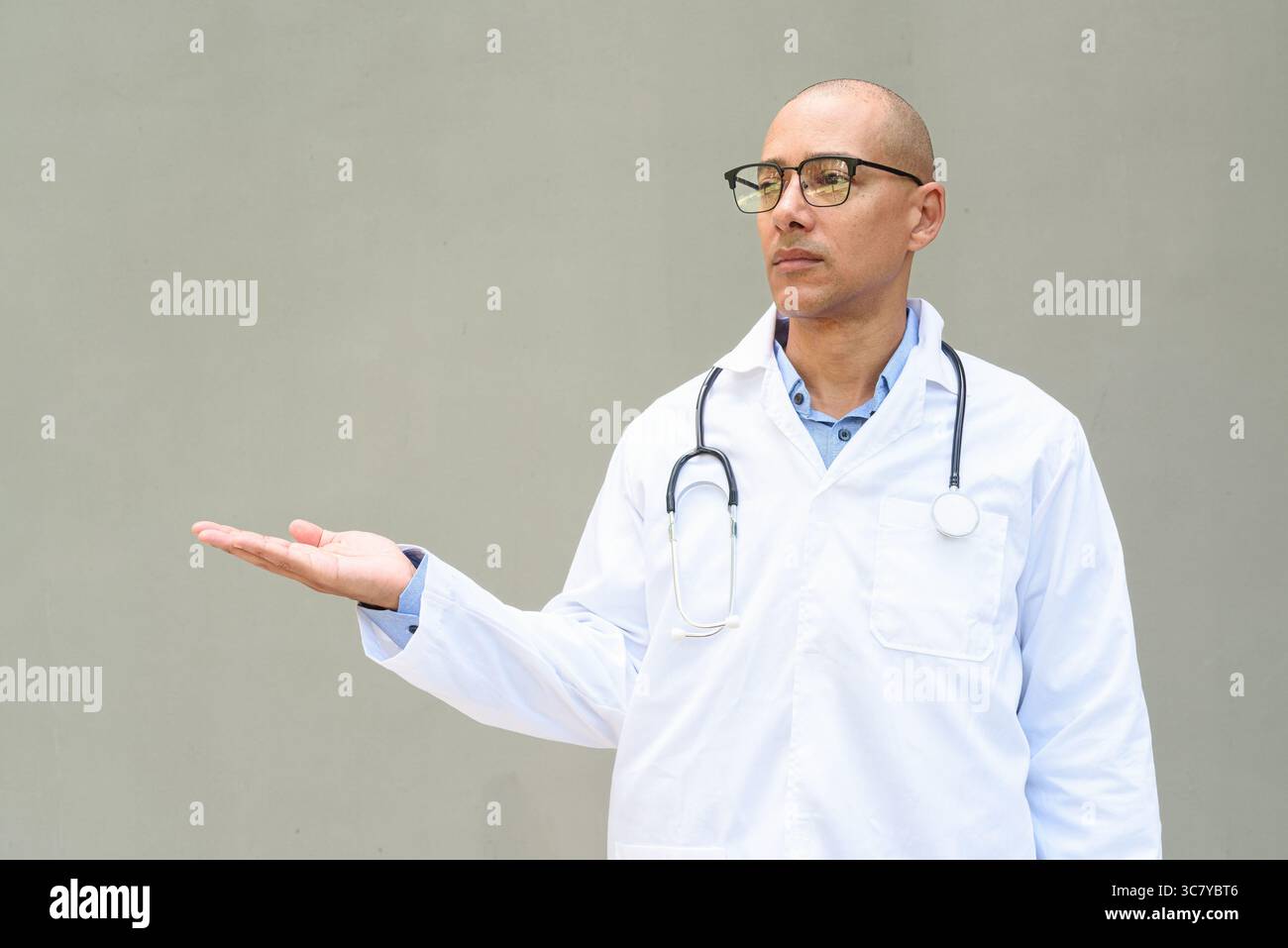 Portrait of mature bald male doctor wearing lab coat and eyeglasses ...