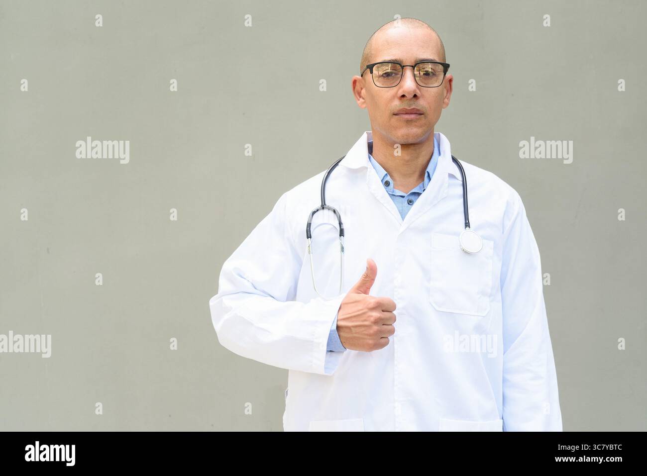 Portrait of mature bald male doctor wearing lab coat and eyeglasses ...