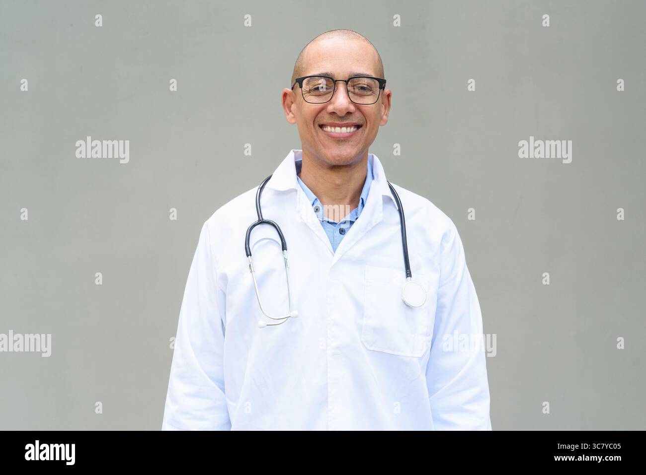 Portrait of mature bald male doctor wearing lab coat and eyeglasses ...